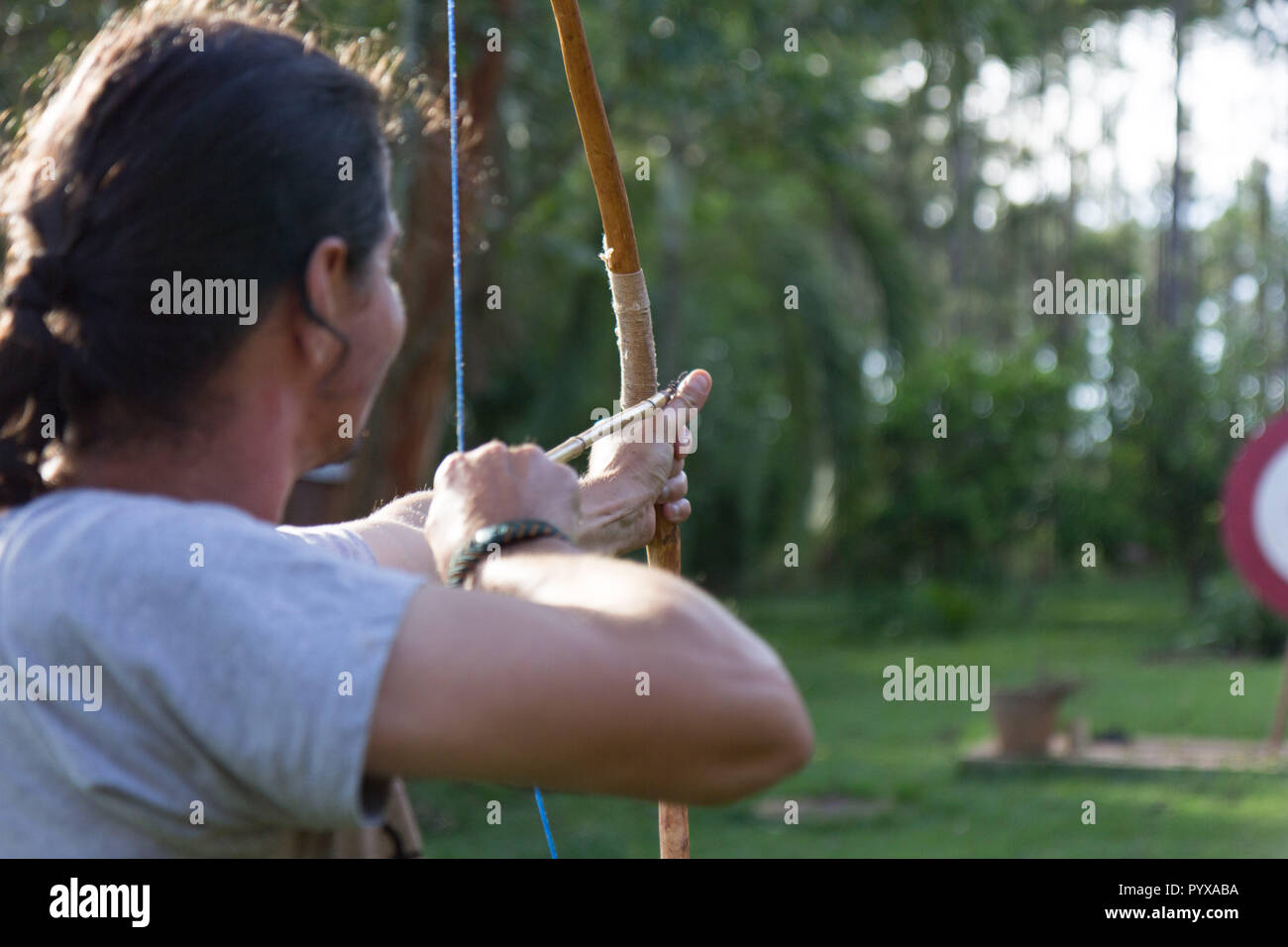 A male sport archer shooting an arrow with a bow at a red wooden target ...
