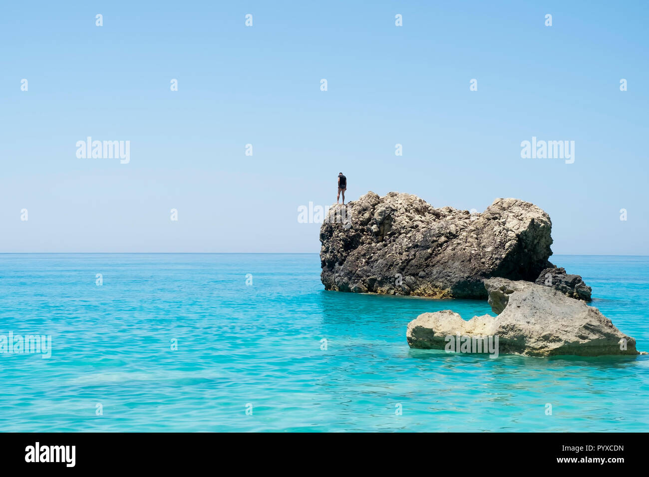 Man standing on rock surrounded by the sea Stock Photo - Alamy
