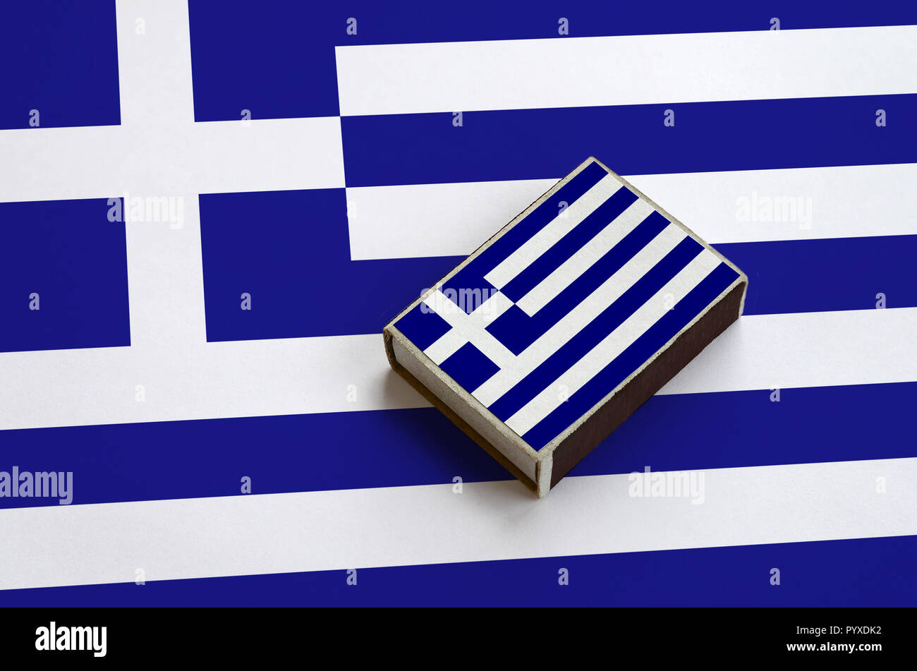 Greece flag is pictured on a matchbox that lies on a large flag Stock ...