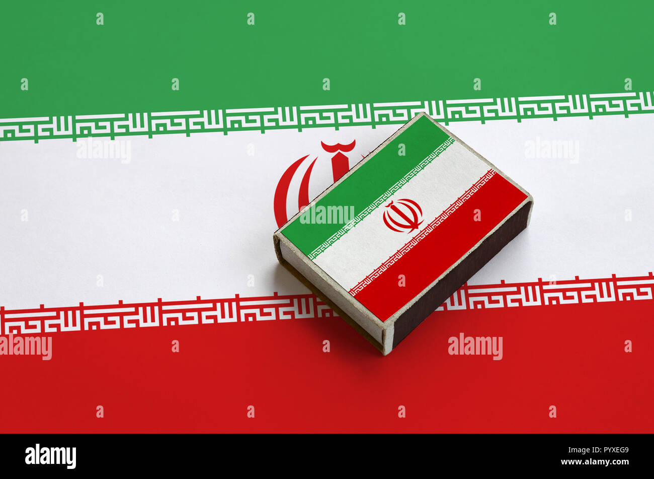 Iran flag is pictured on a matchbox that lies on a large flag Stock ...