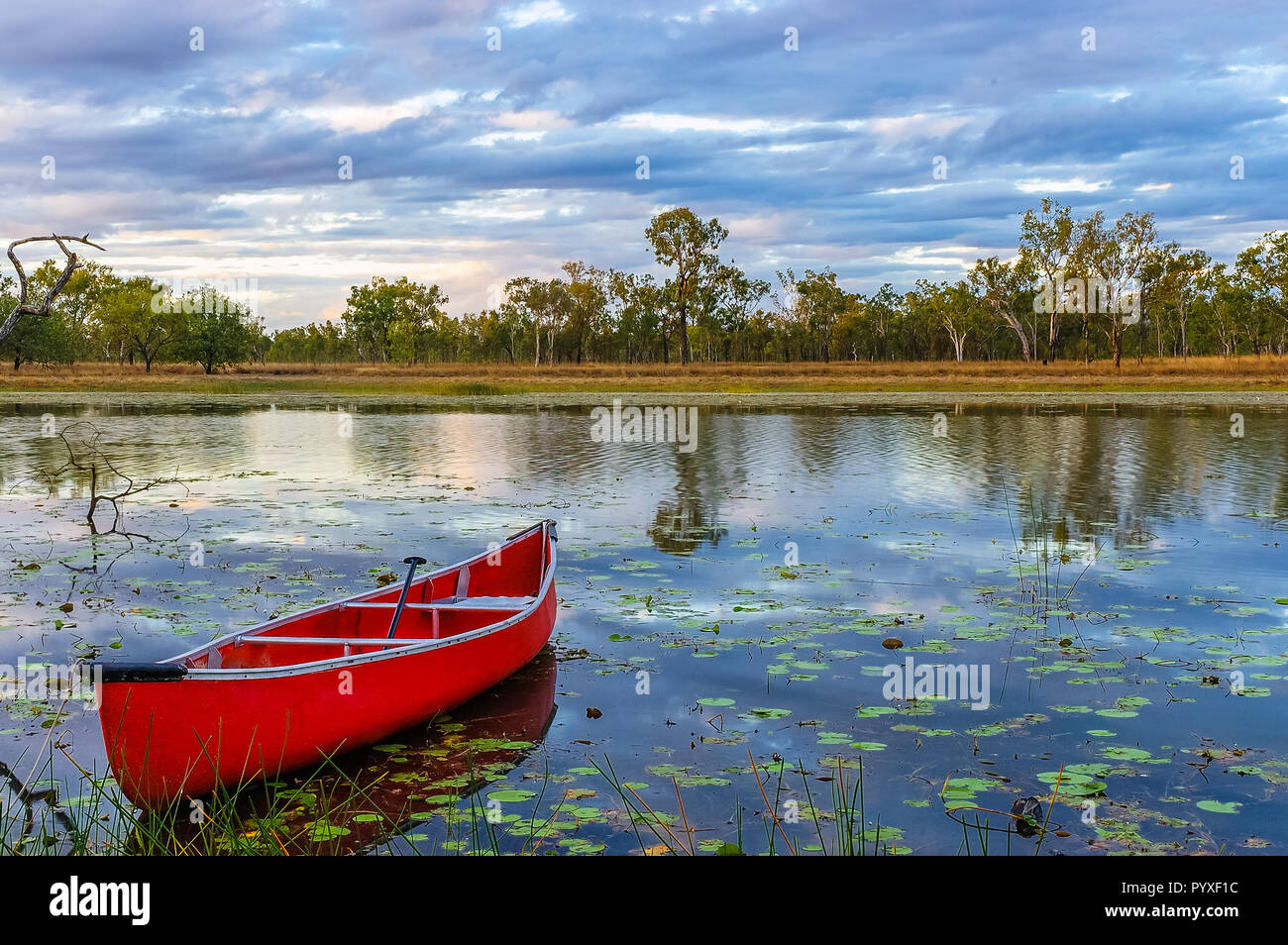 A red canoe moored at a wilderness camp on a wetland lagoon in the ...
