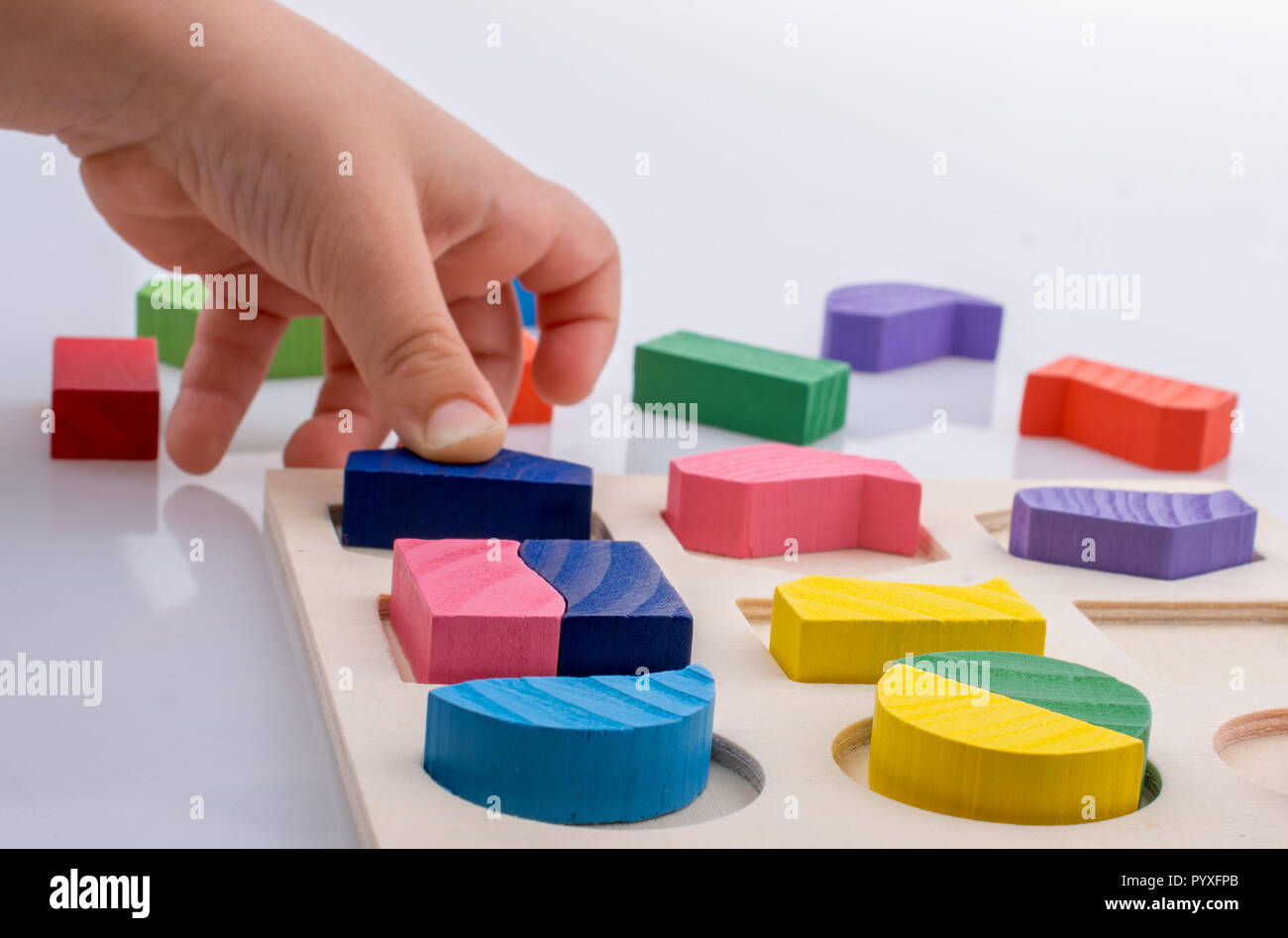 Colorful wooden pieces of a logic puzzle in hand Stock Photo - Alamy