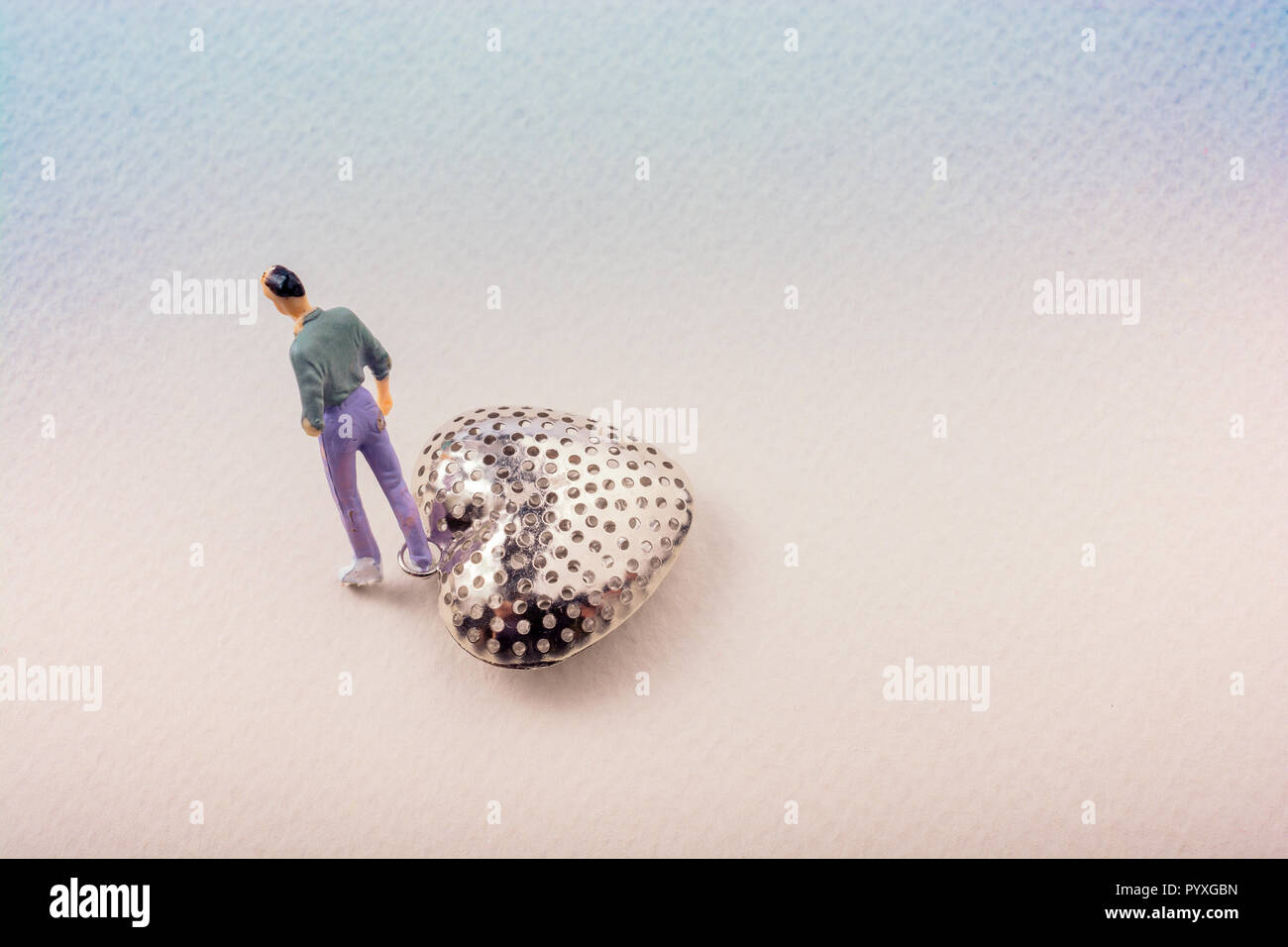 Tiny figurine of man with attached to a heart icon Stock Photo - Alamy