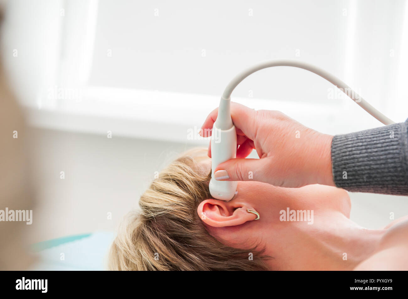 Adult woman doctor scanning head vessels on the head with ultrasound ...