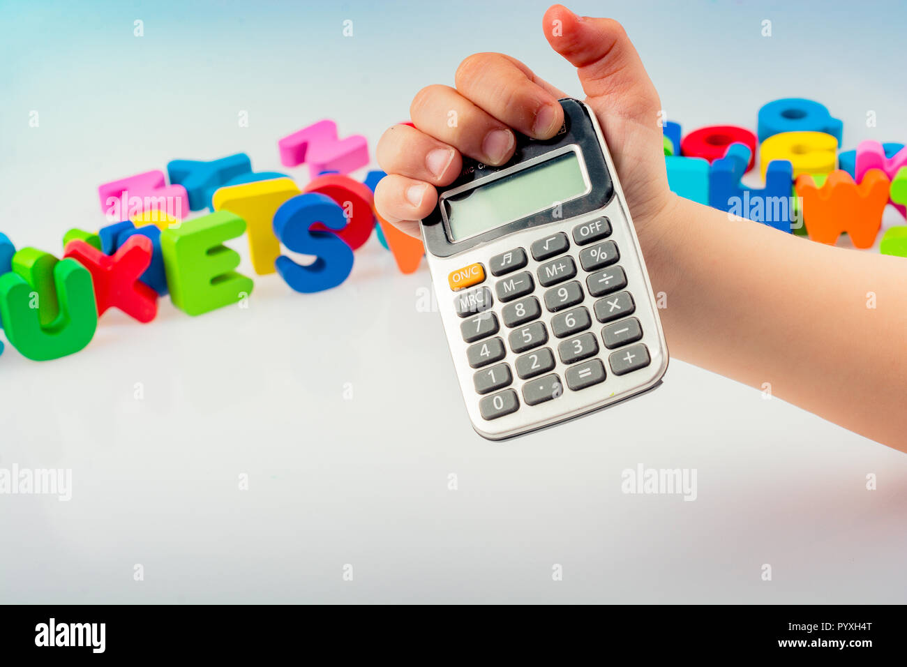 Little calculator in hand with colorful letters behind on white Stock ...