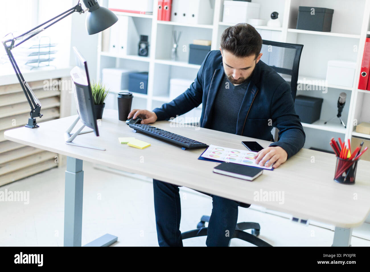 The young man works in the office at a computer Desk with documents ...