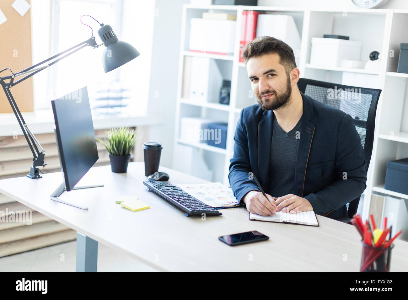 The young man works in the office at a computer Desk with documents ...