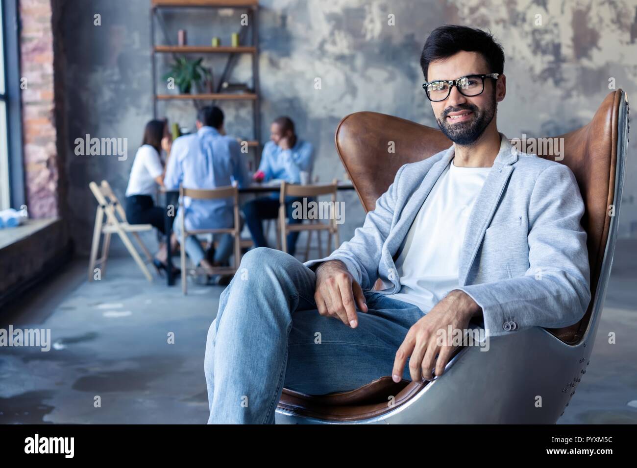 Young corporate executive sitting comfortably in a stylish chair in ...