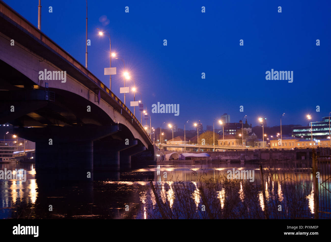 Night city landscape with bridge over river and beautiful glowing ...