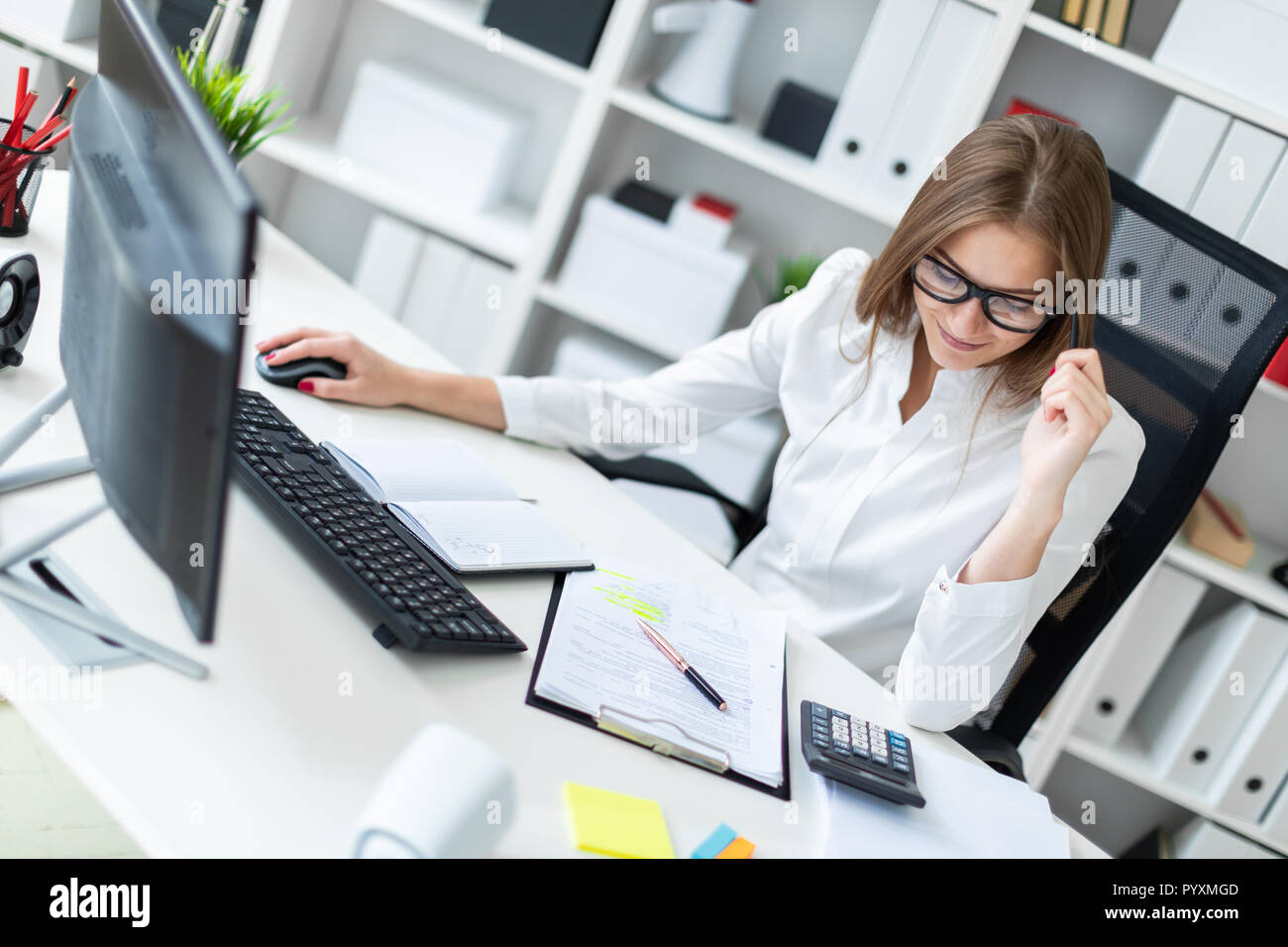 Young girl sitting at the table and working with a computer, documents ...