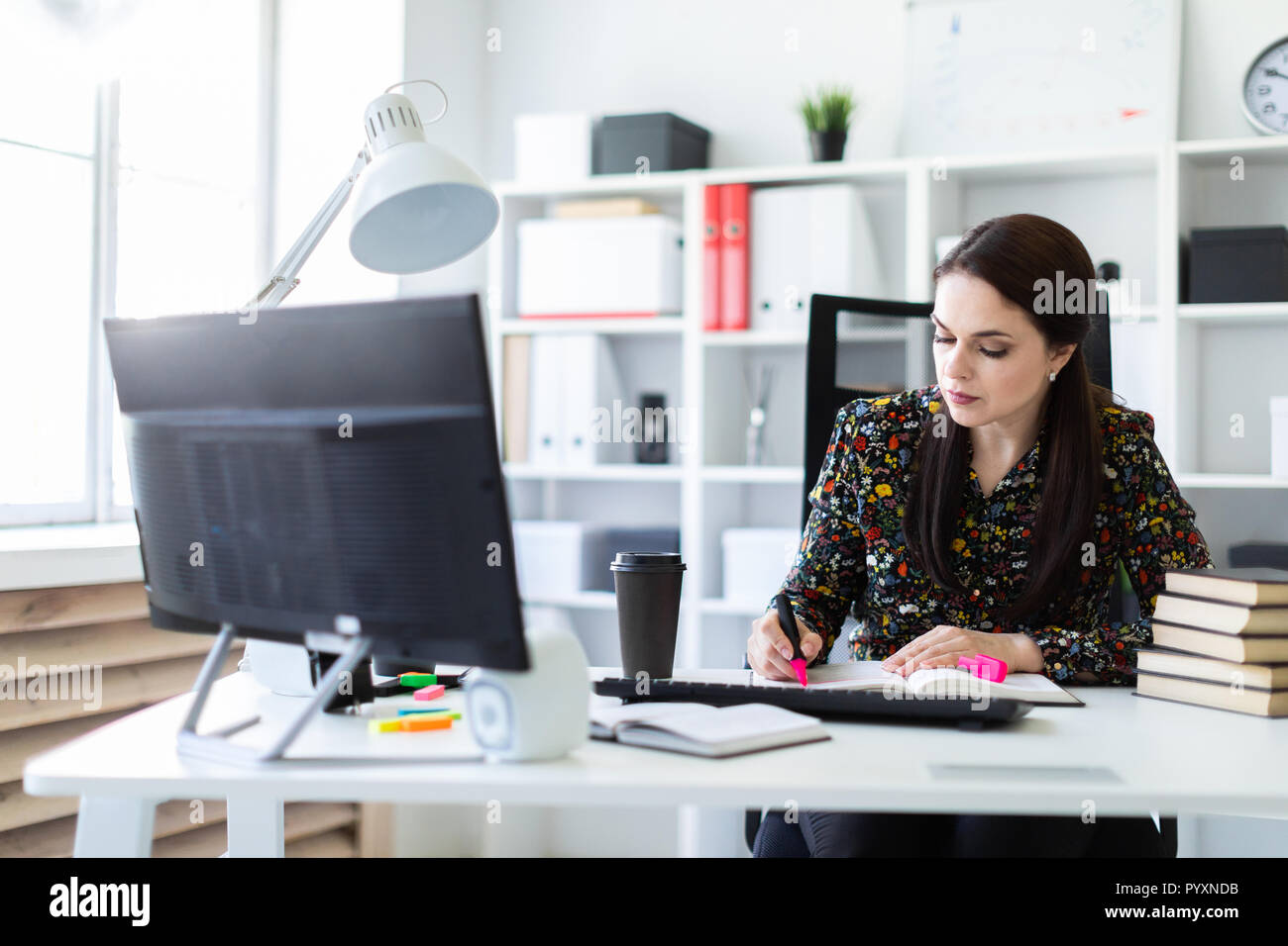 A young girl sitting in the office at the computer Desk and working ...