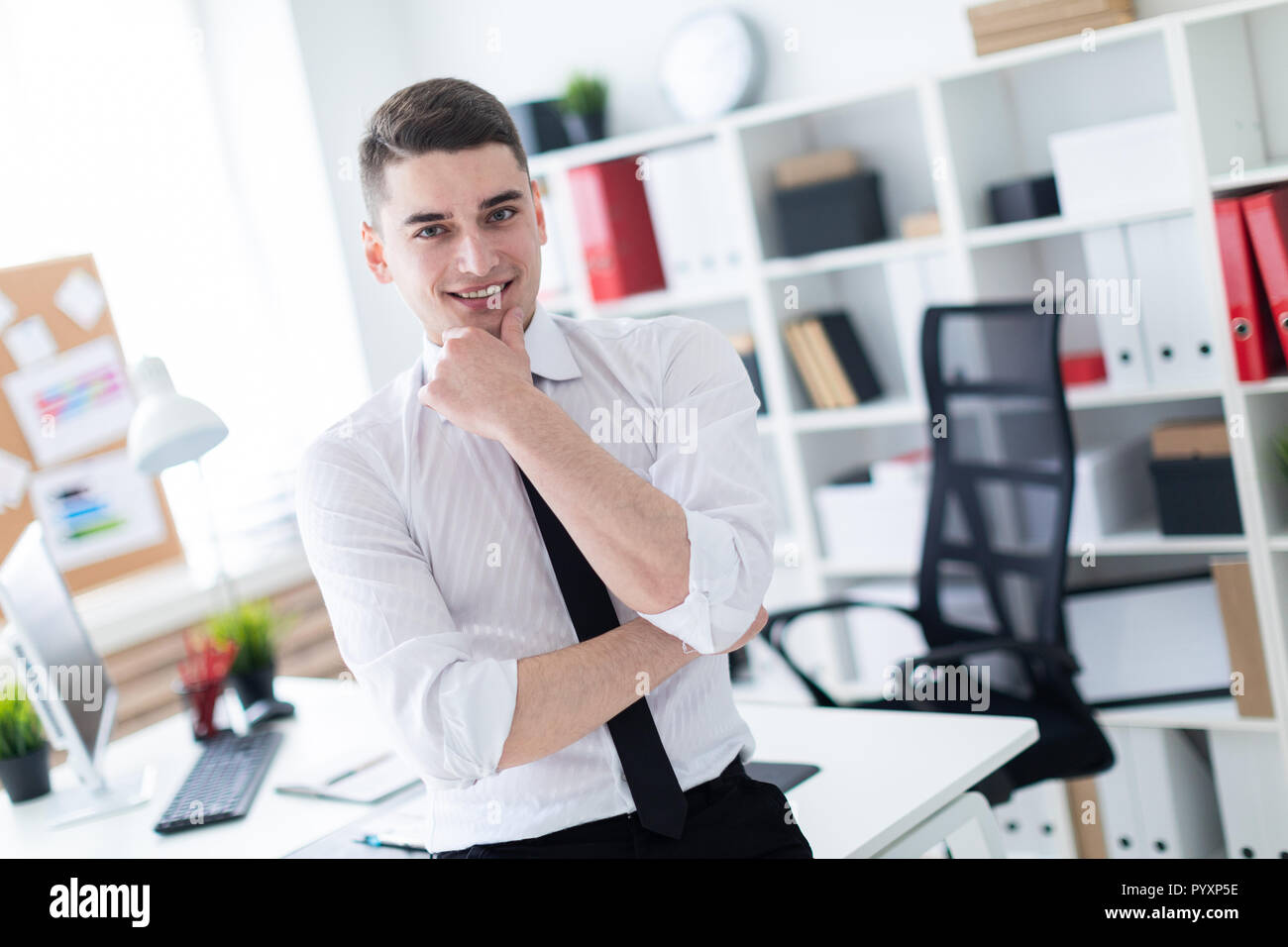 The young man stands in the office leaning on the table Stock Photo - Alamy