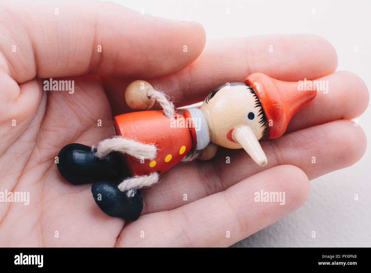 Wooden pinocchio doll in hand on a white background Stock Photo - Alamy