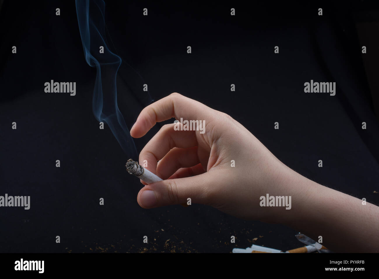 Hand is holding smoking cigarette with smoke around Stock Photo - Alamy