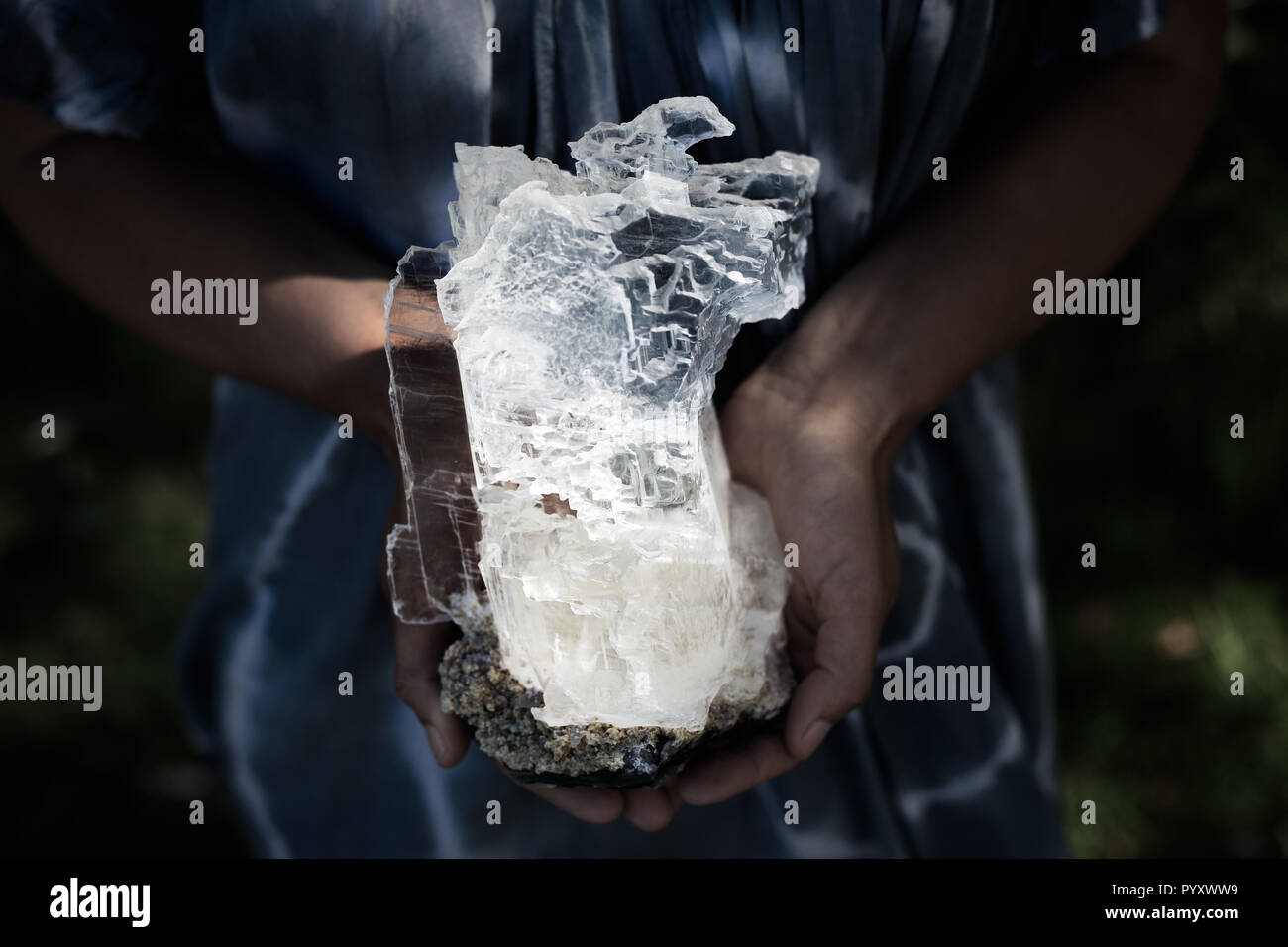 A close up of a woman holding, dark, powerful selenite crystal on geode ...