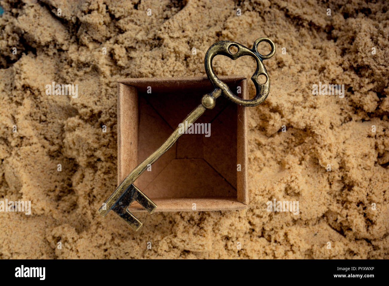 Retro style key placed in a brown box on sand Stock Photo - Alamy