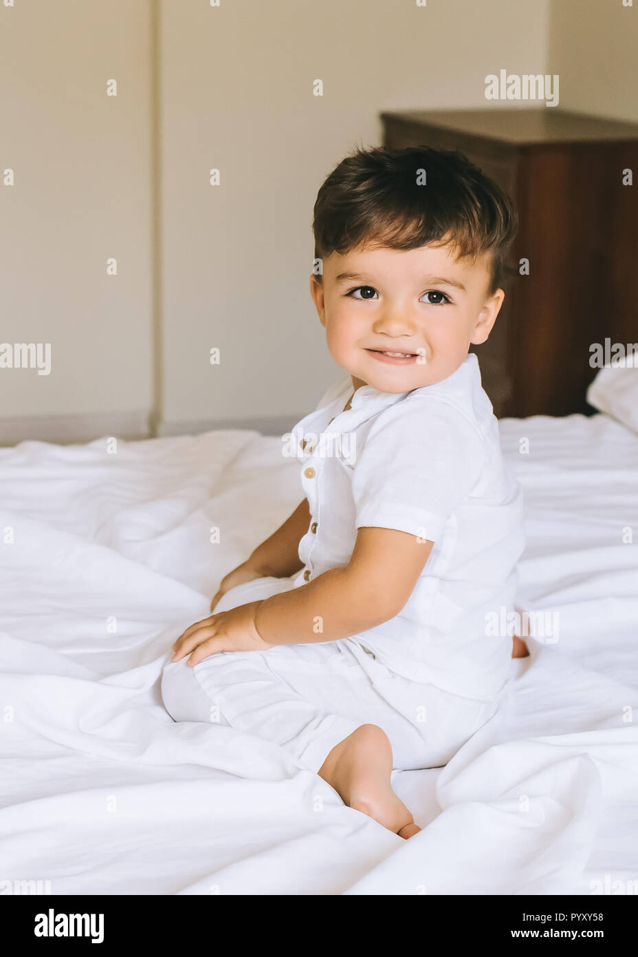 cute little child sitting on bed and looking back Stock Photo - Alamy