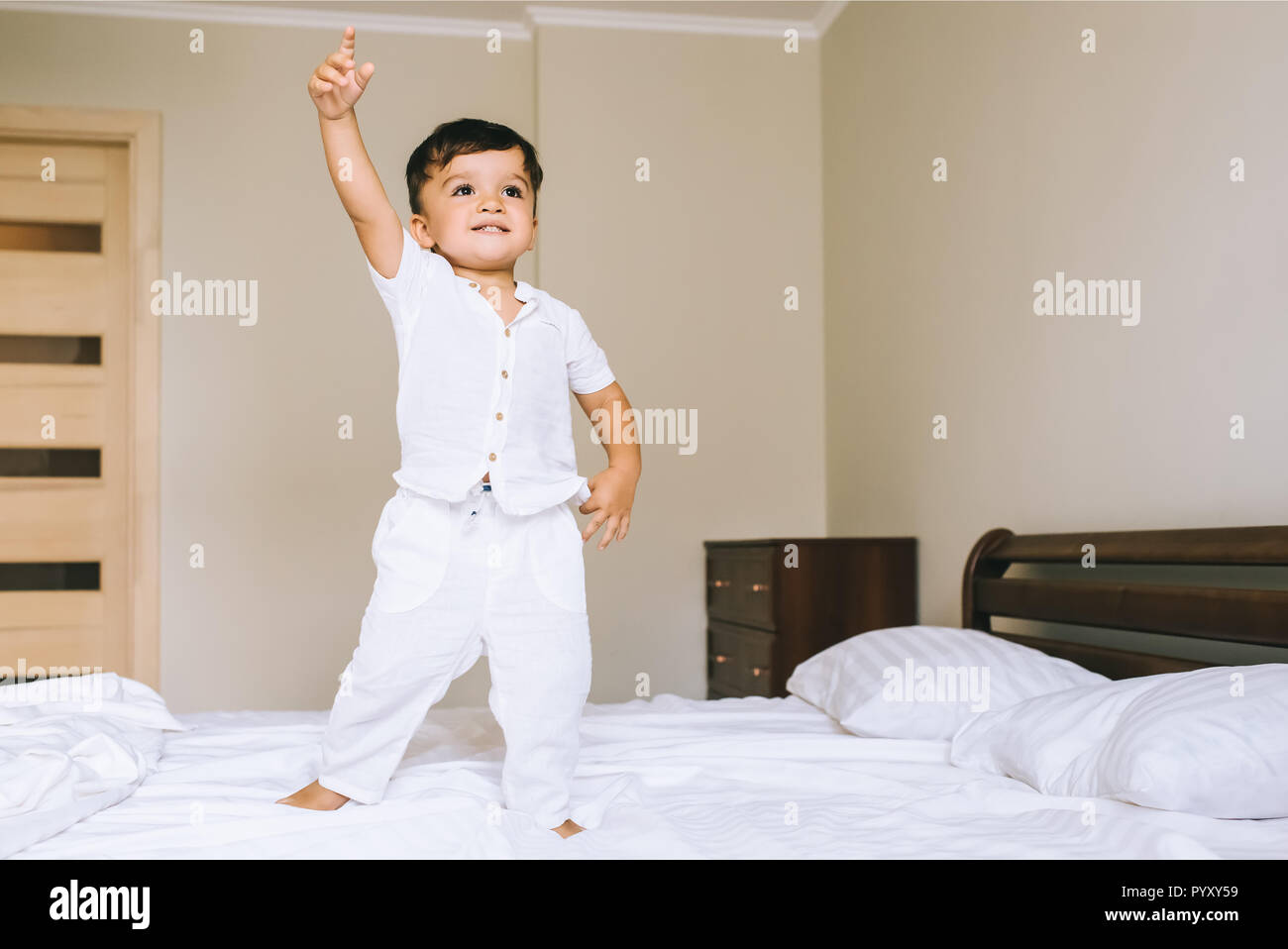 adorable little kid standing on bed and pointing somewhere Stock Photo ...