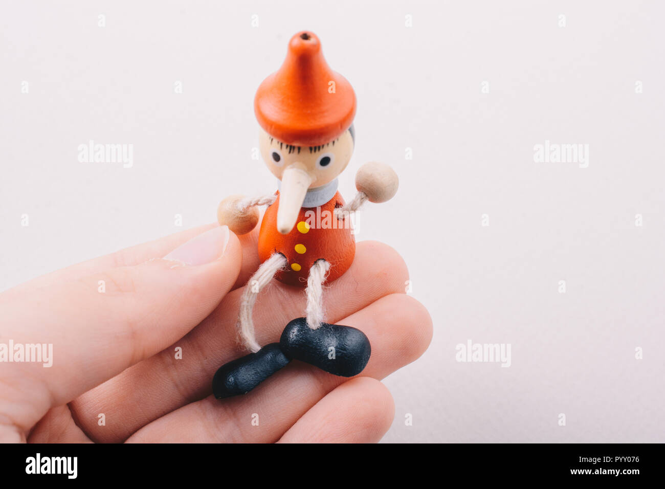 Wooden pinocchio doll in hand on a white background Stock Photo - Alamy