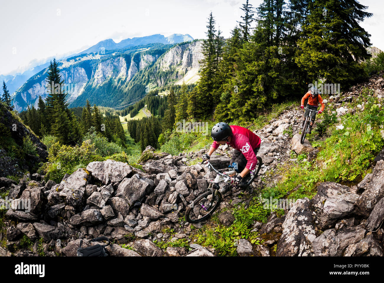 Mountain bikers riding a very difficult rocky trail with cliffs and ...
