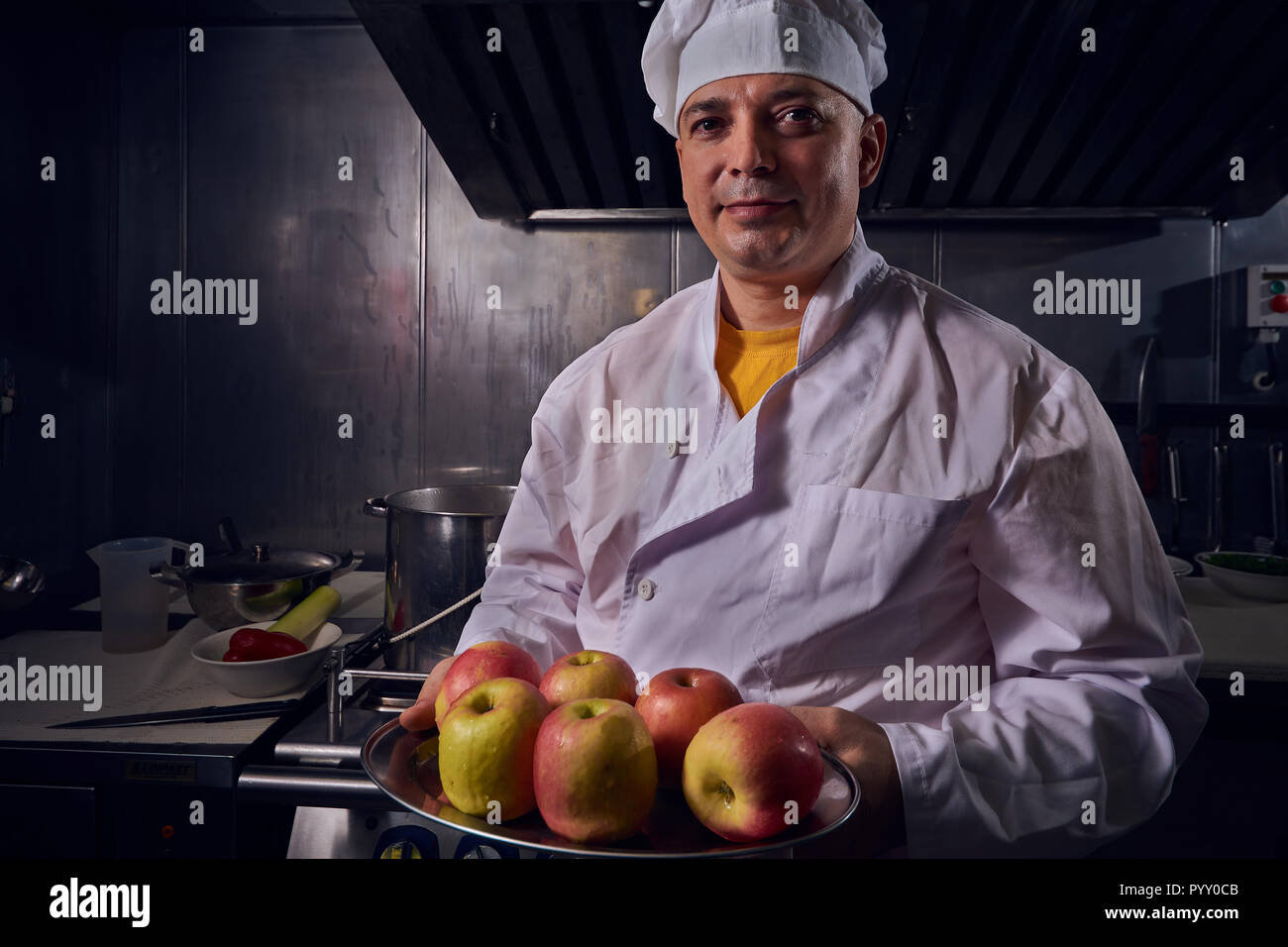 Professional chef cook in a white apron and cooks hat prepairing ...