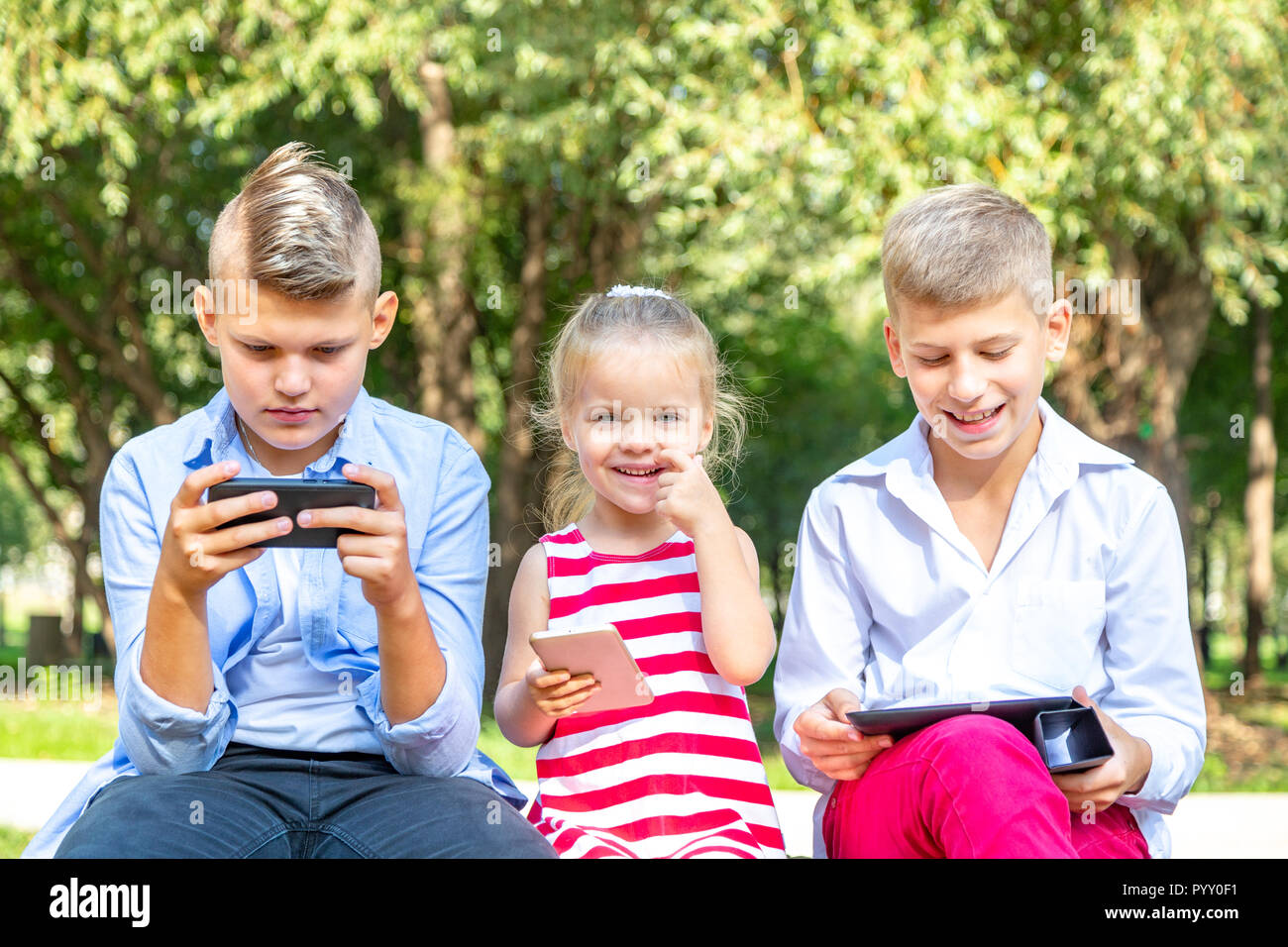 Group of busy kids looking at their phones texting sms and playing ...