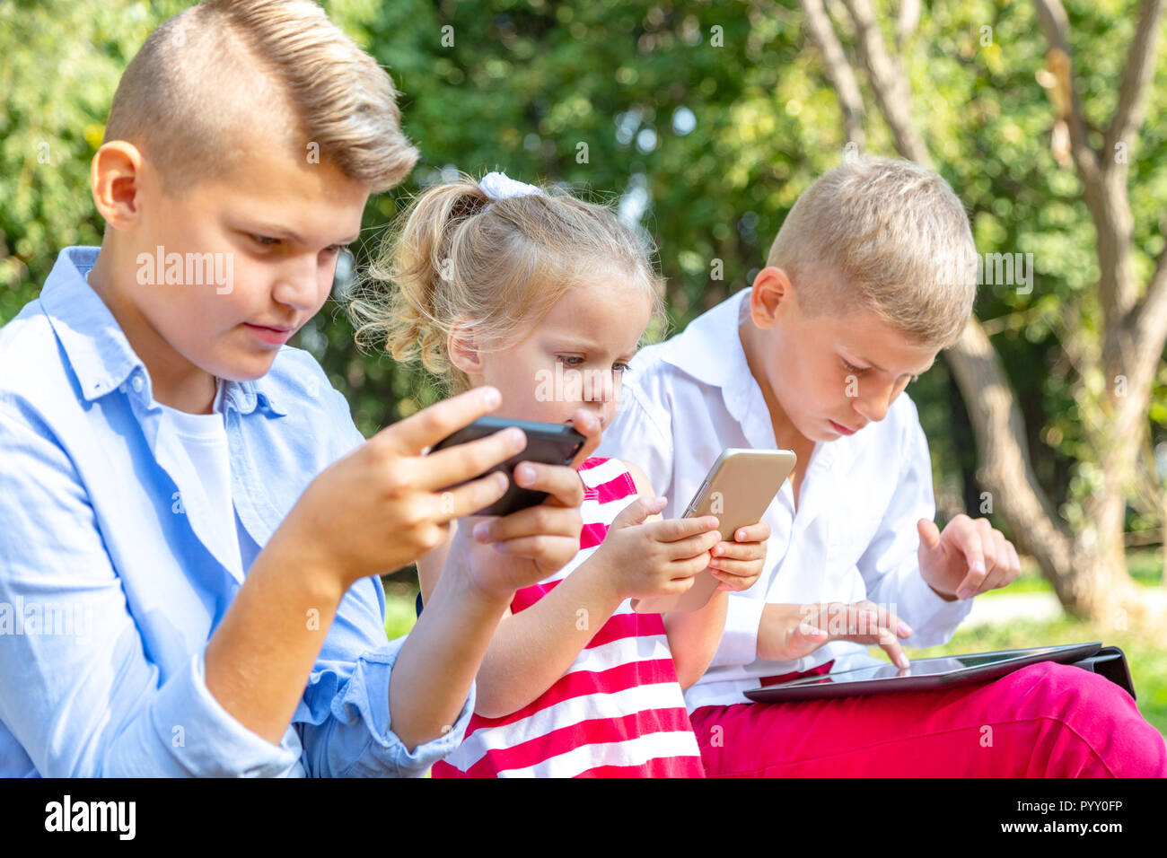 Group of busy kids looking at their phones texting sms and playing ...