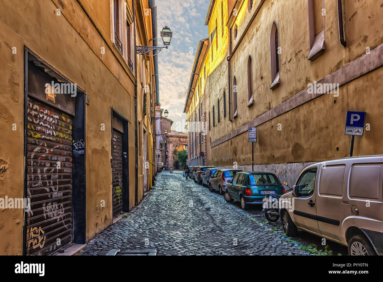 Typical Roman Street with an old gate and cars parked Stock Photo - Alamy