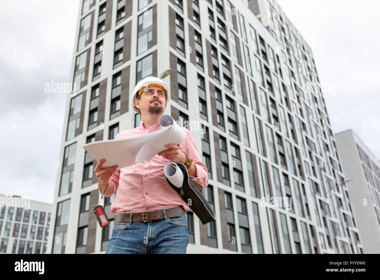 Handsome architect or supervisor standing outdoors on a building site ...