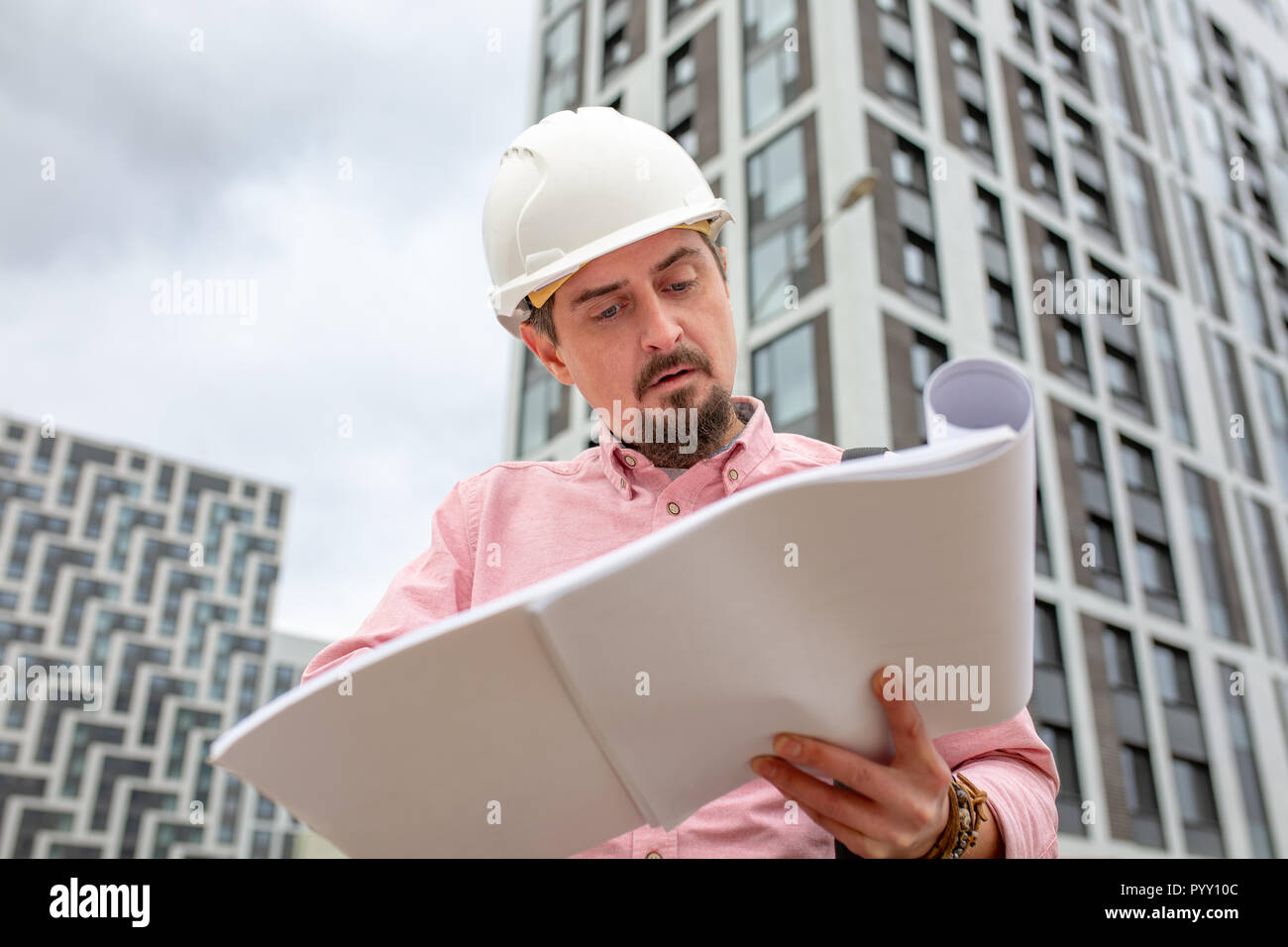 Handsome architect or supervisor standing outdoors on a building site ...