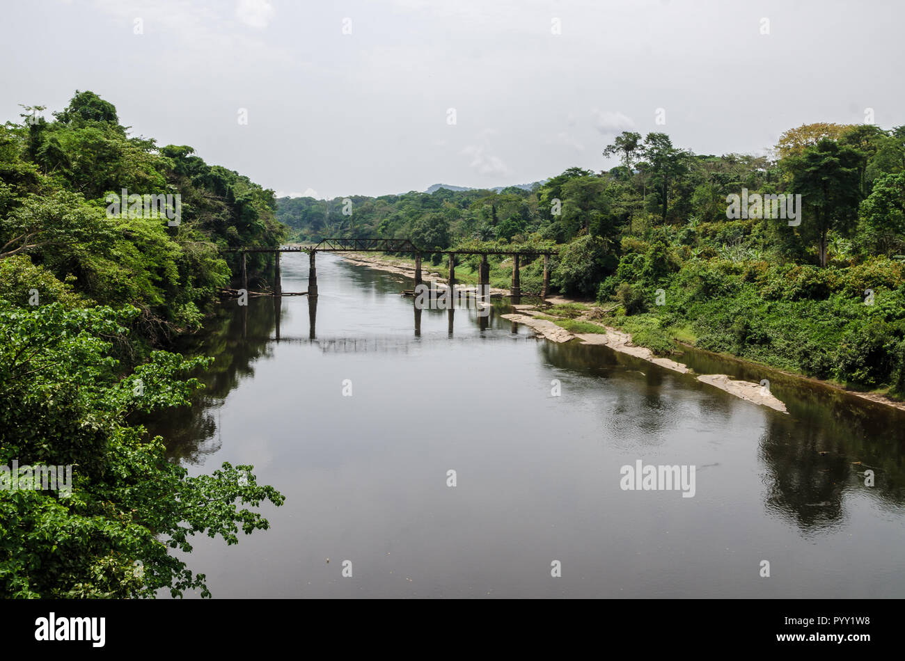 Crumbling iron and concrete bridge crossing Munaya river in rain forest ...