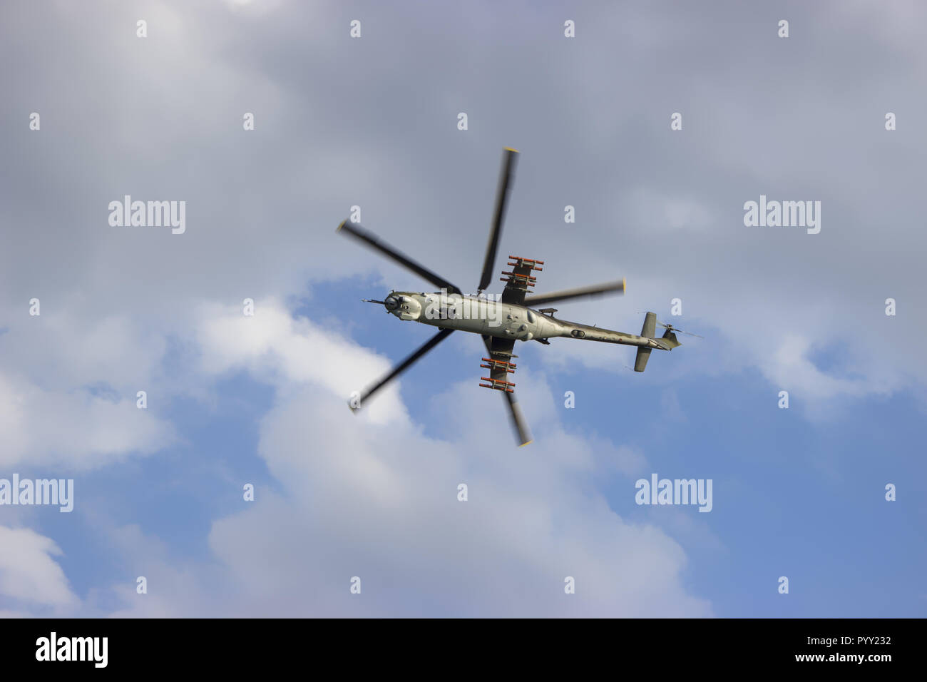 Combat helicopter on blue sky with white clouds. View from the bottom ...