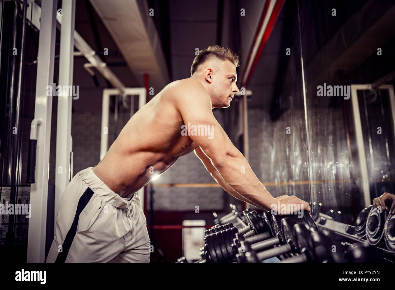 Bodybuilder preparing for heavyweight exercise with barbell in gym ...