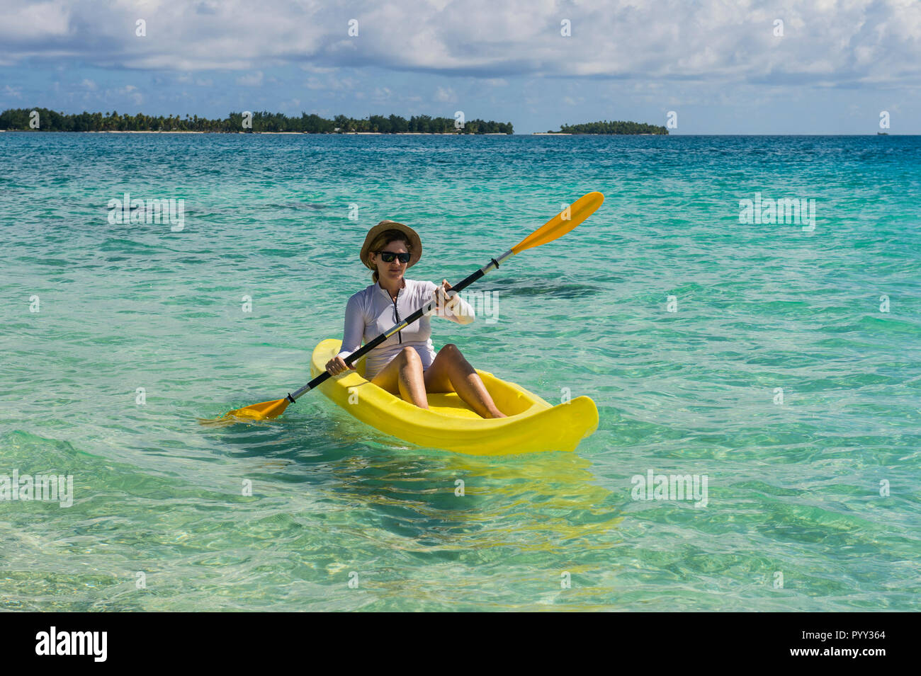 Female tourist kayaking in the turquoise waters of Tikehau, Tuamotu ...