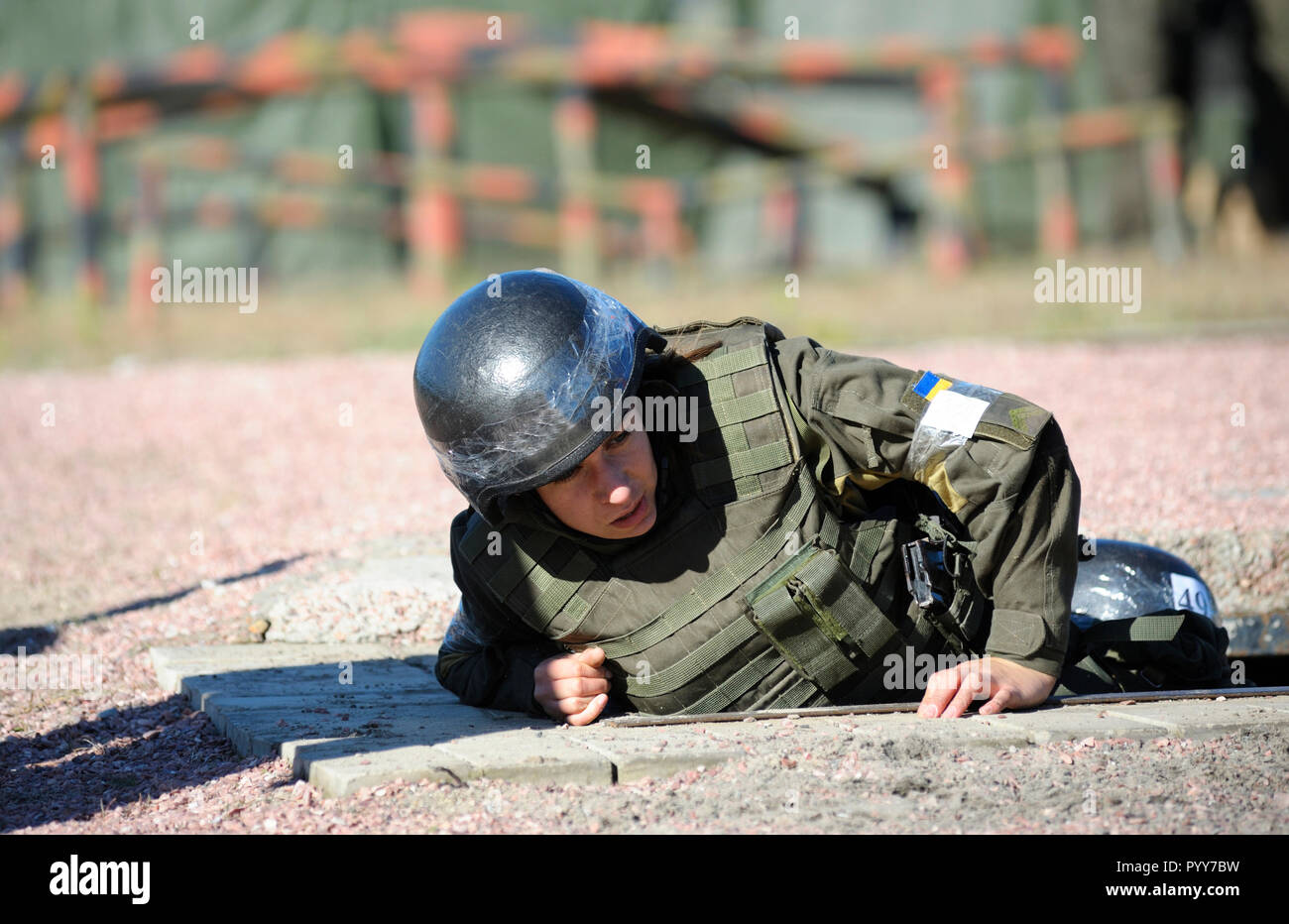 On a military training ground, obstacle course: female soldier crawling ...