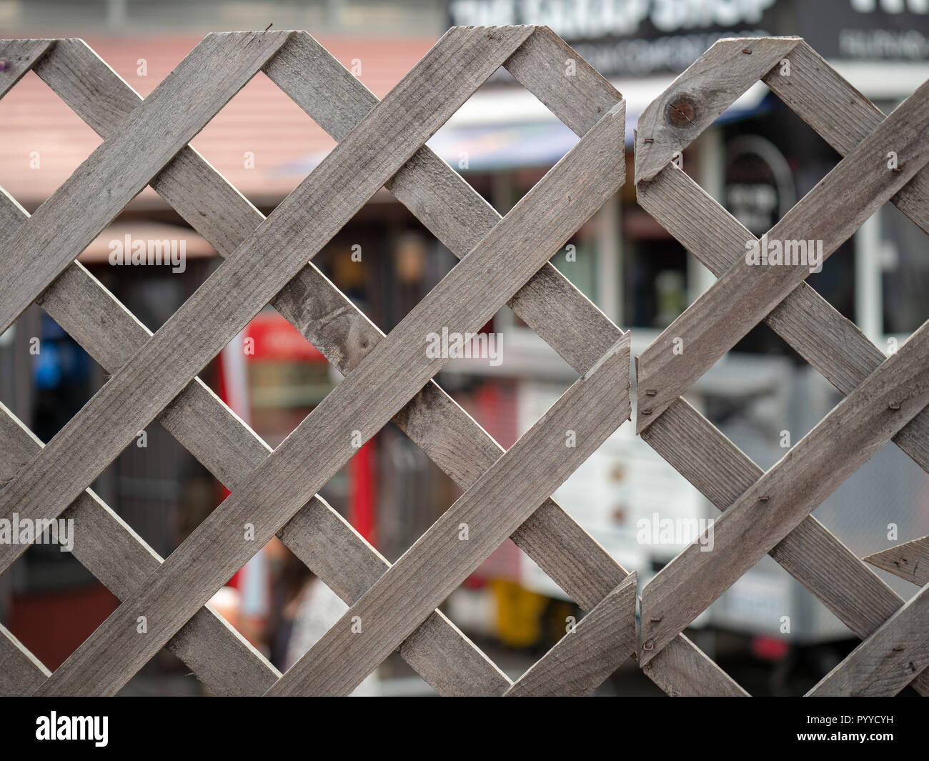 Wooden diamond shaped fence standing in front of a shopping and dining ...
