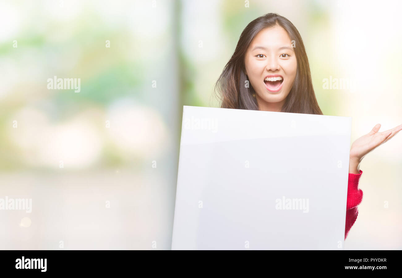 Young asian woman holding banner over isolated background very happy ...