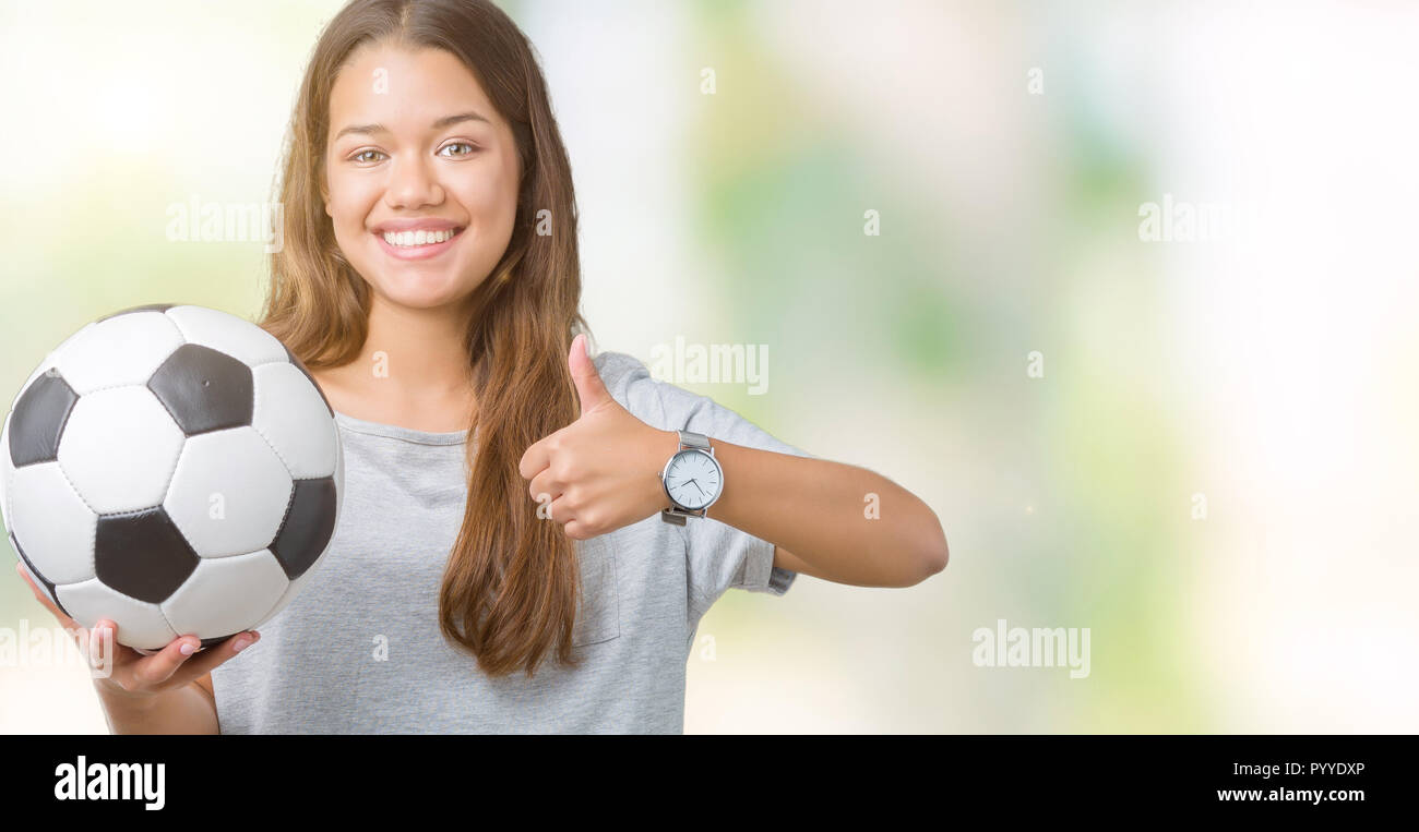 Young beautiful brunette woman holding soccer football ball over ...