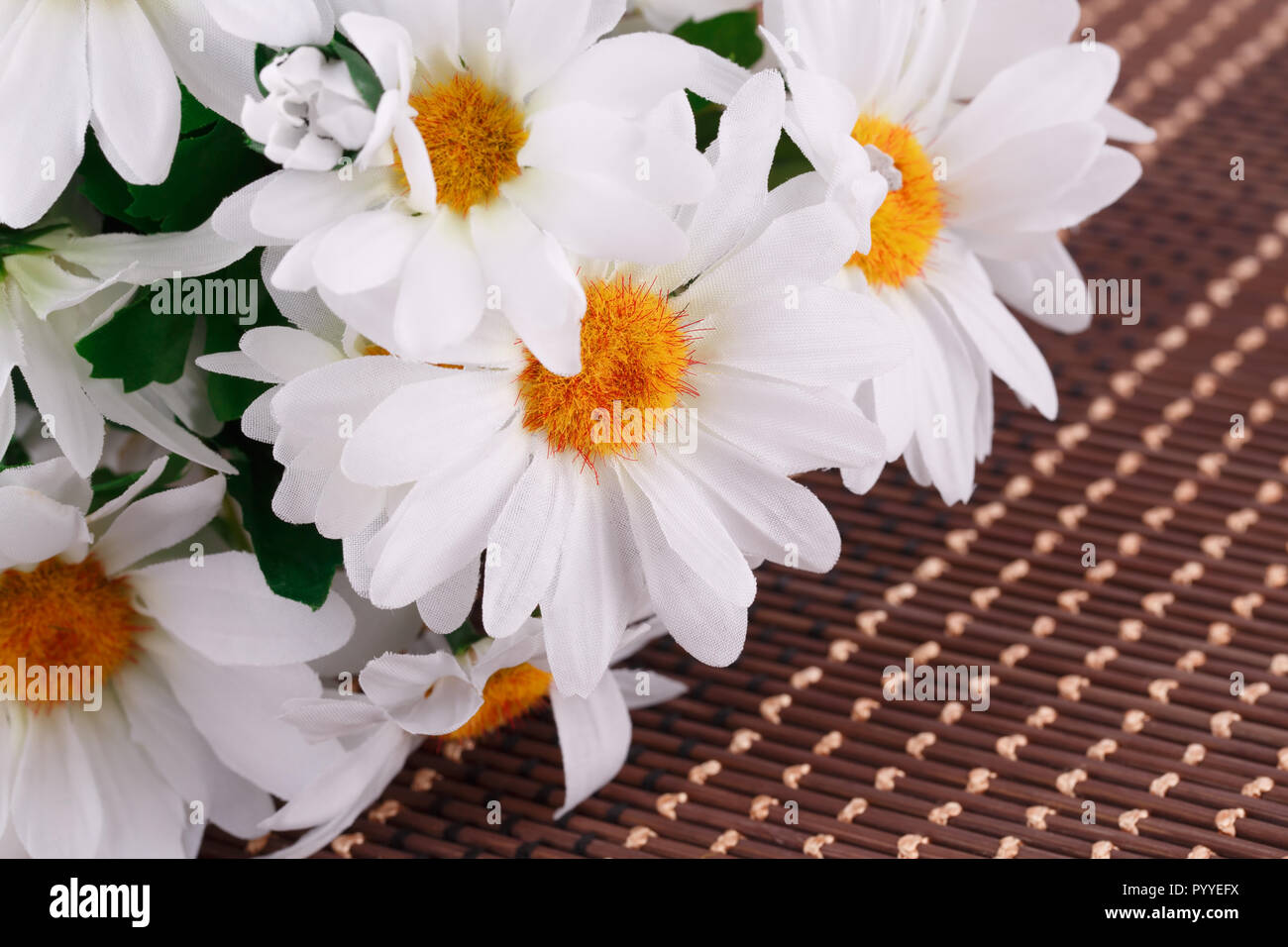 White fabric daisies on bamboo background, closeup picture Stock Photo ...