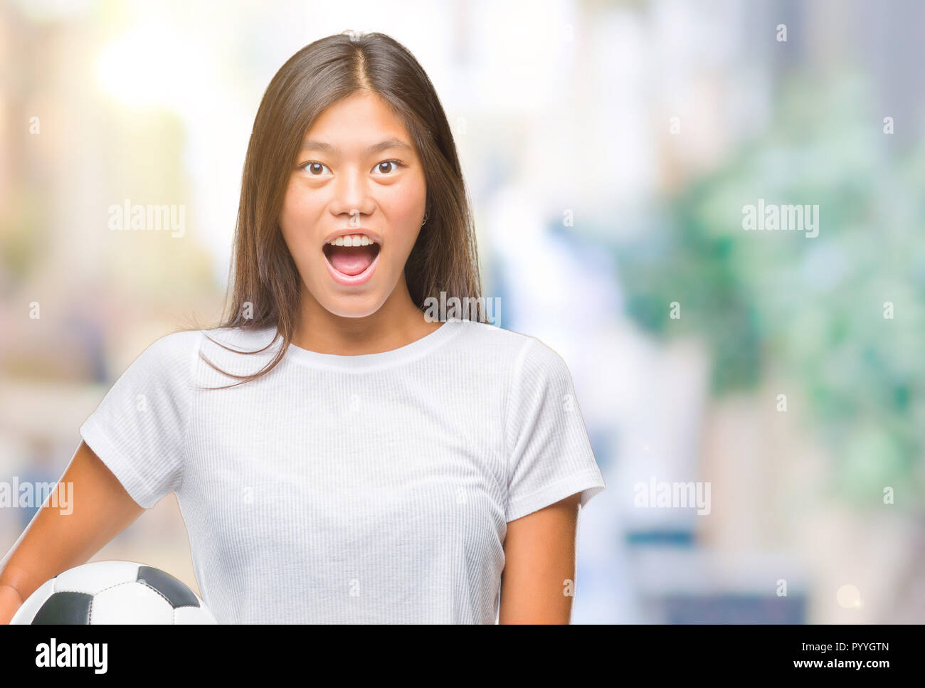 Young asian woman holding football soccer ball over isolated background ...
