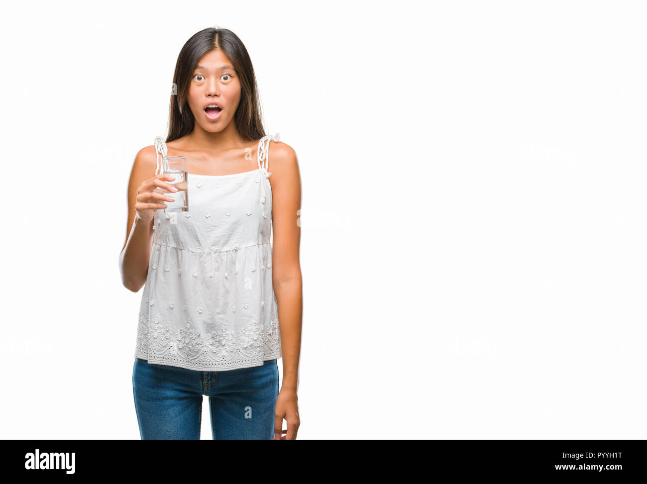 Young asian woman drinking glass of water over isolated background ...