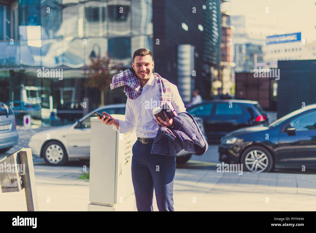 An urban businessman is outside on a windy day, holding notebook and ...