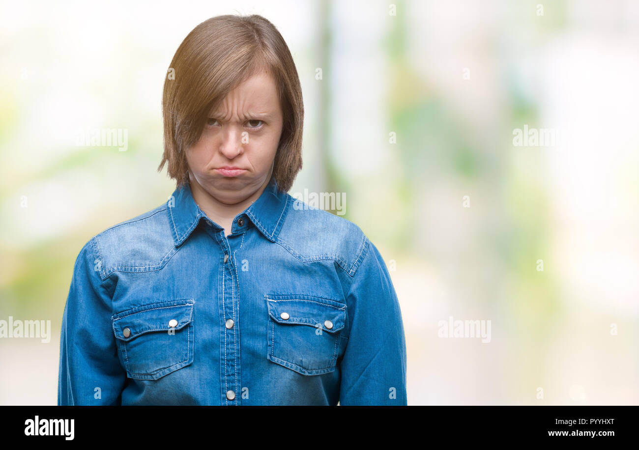 Young adult woman with down syndrome over isolated background depressed ...