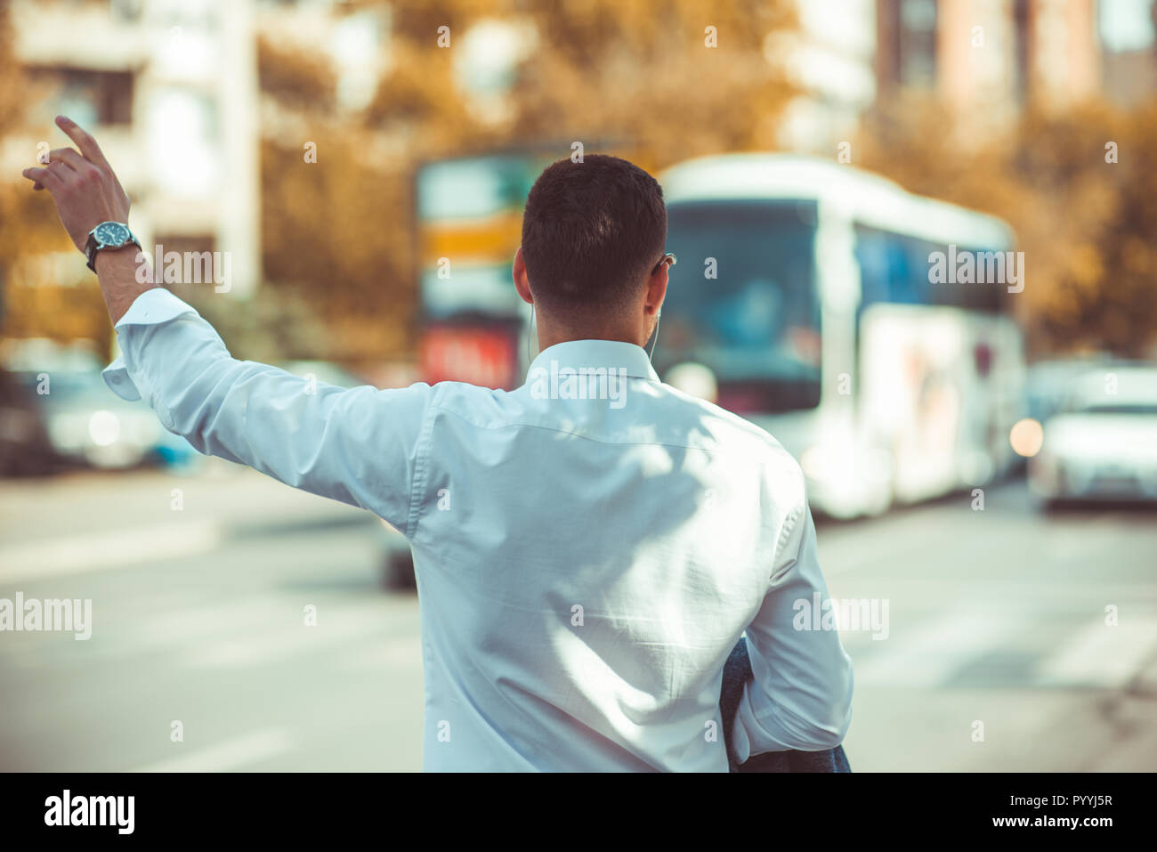 Modern businessman is trying to catch a bus so he pulls his hand up, he ...