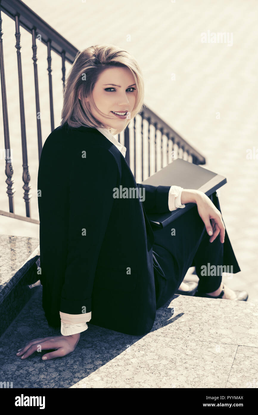 Happy young business woman with file folder sitting on steps Stock ...