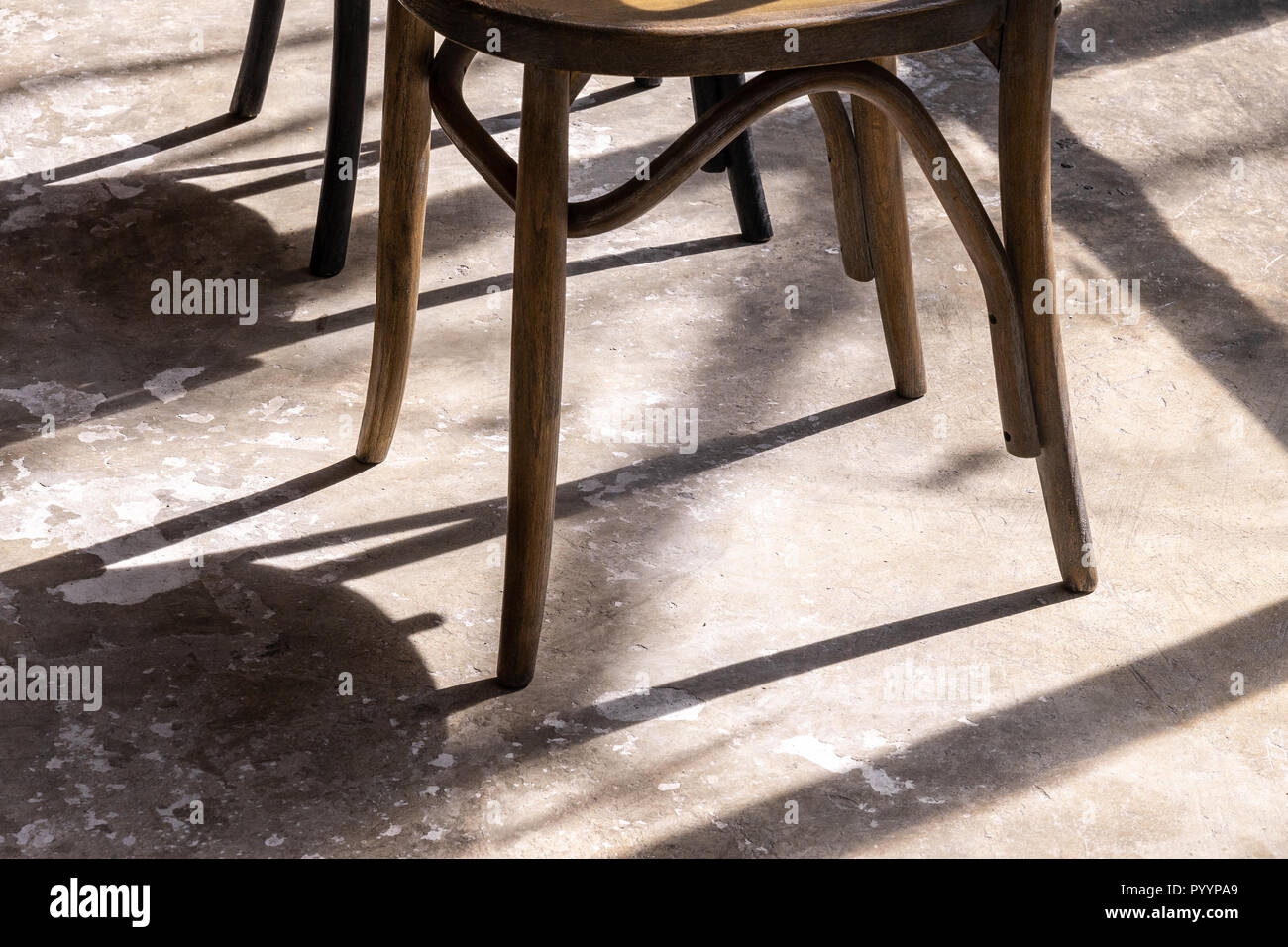 close up wooden chair legs with shadow and light on grunge cement ...