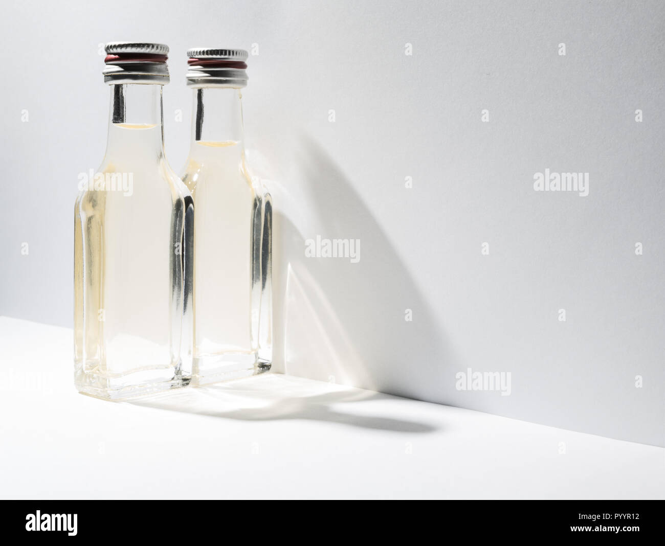 Two bottles of vintage alcohol near the wall with oblique shadows on a white background Stock ...