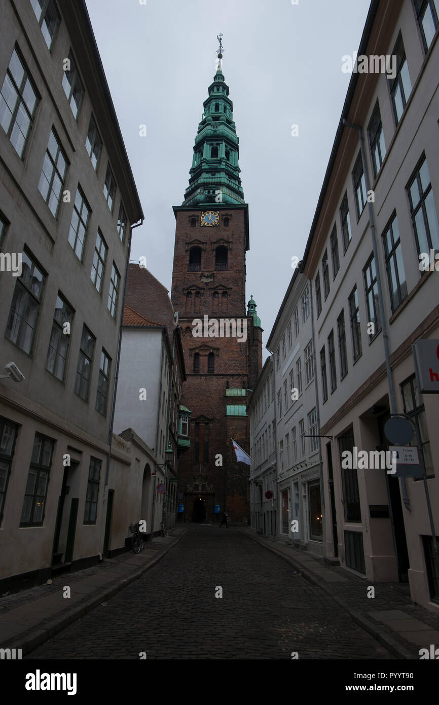 A clock tower at the end of an alley in Copenhagen, Denmark in winter ...