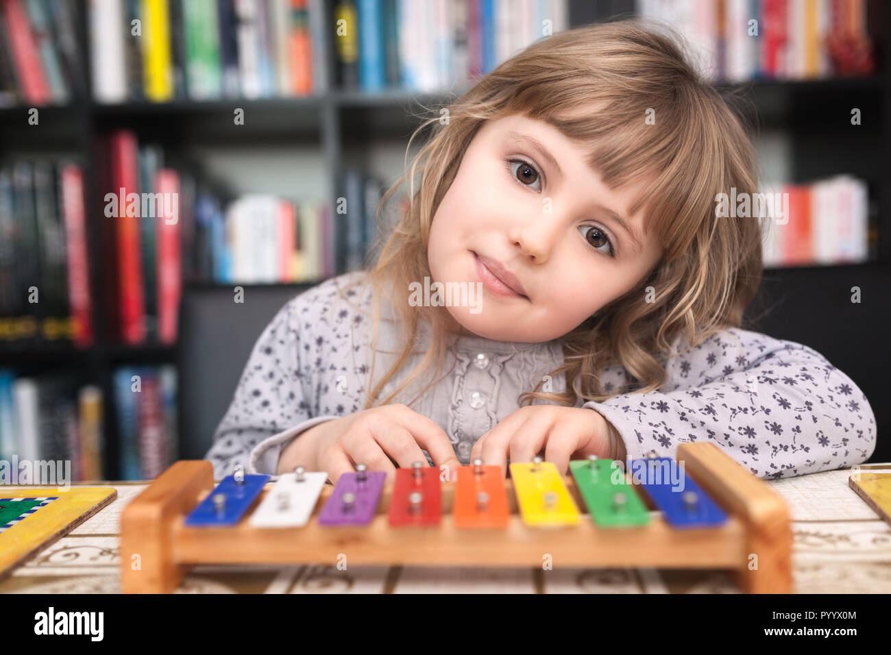Cute little Caucasian girl playing little colorful cymbals at home ...