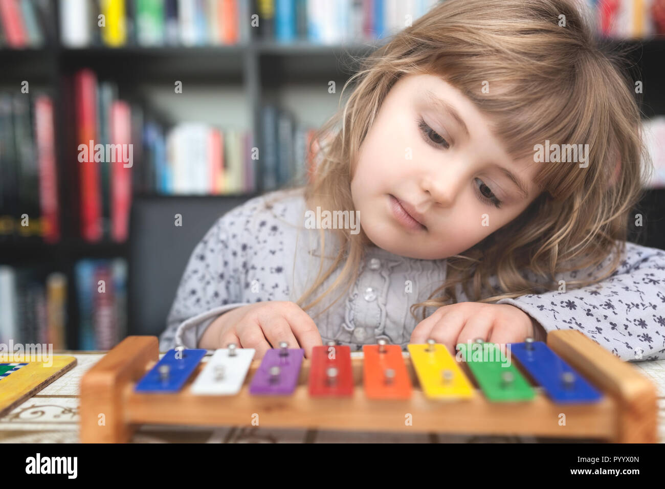 Cute little Caucasian girl playing little colorful cymbals at home ...
